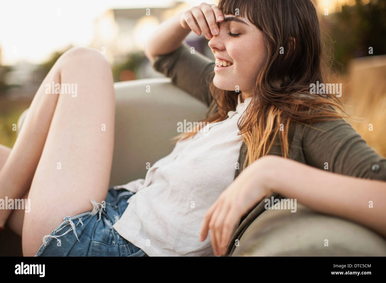 Young woman reclining on seat outdoors Stock Photo - Alamy