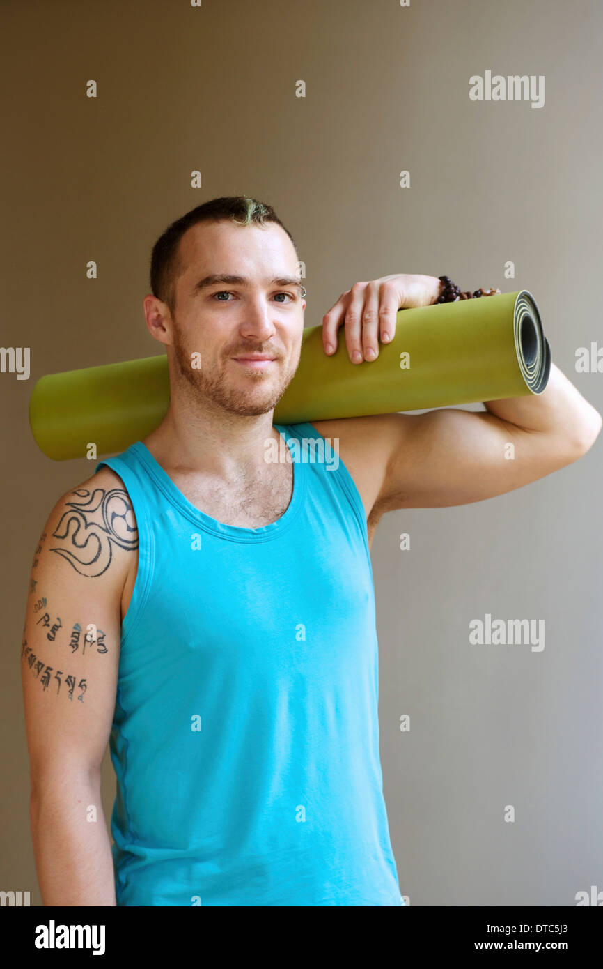 Portrait of man holding yoga mat Stock Photo - Alamy
