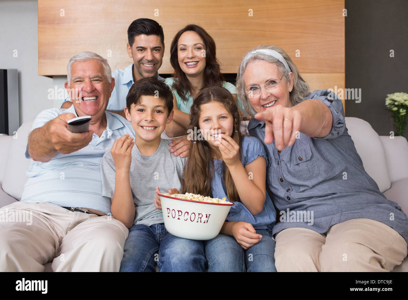 Portrait of happy extended family watching tv in living room Stock ...