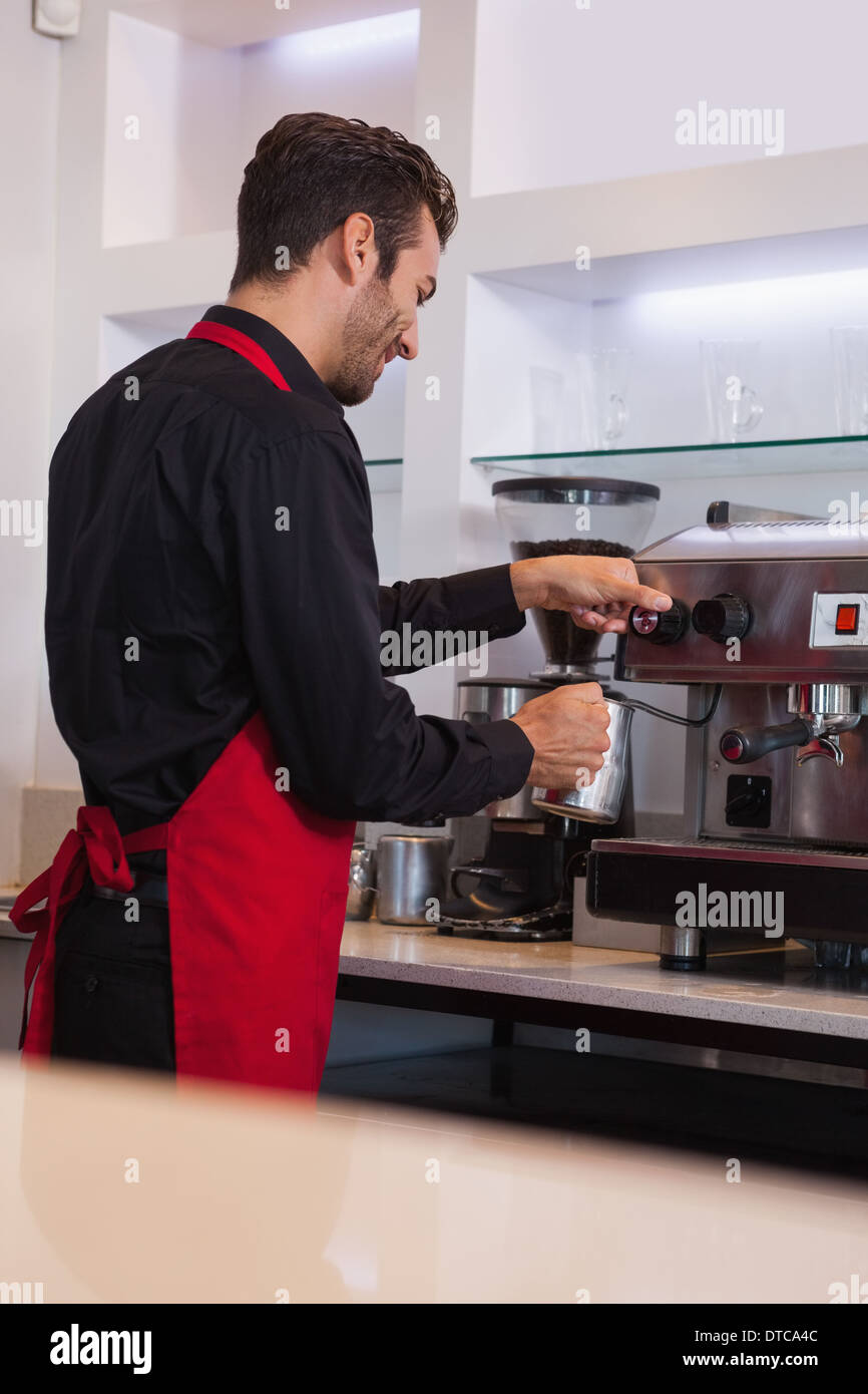 Smiling young barista steaming jug of milk in a cafe Stock Photo - Alamy