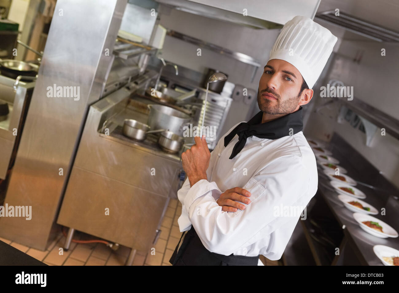 Focused chef looking at camera with arms crossed holding ladle Stock ...