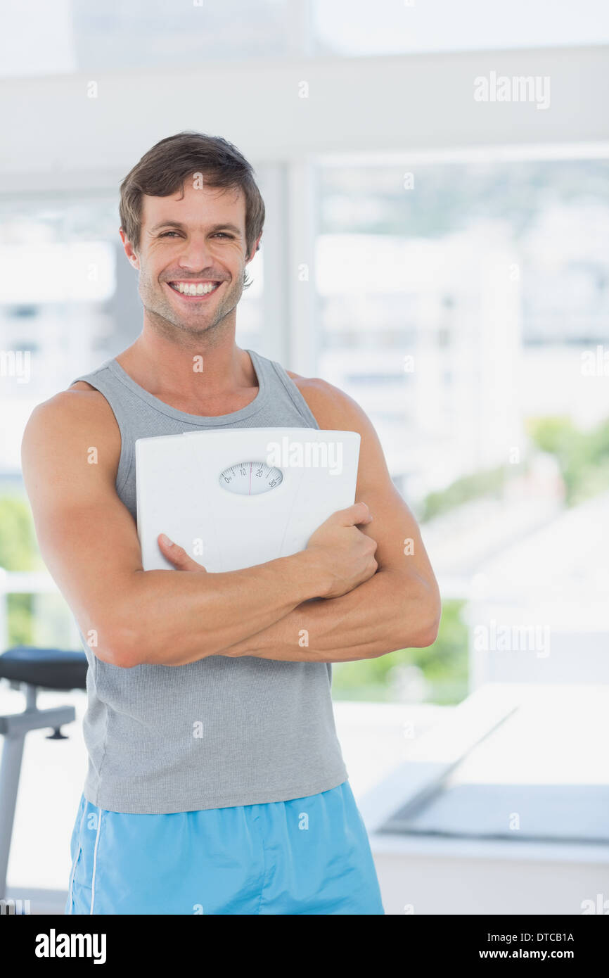 Fit man standing with scale in bright exercise room Stock Photo - Alamy