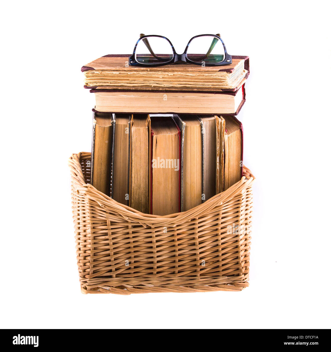 Stack of old antique books in a wicker basket and spectacles lying on ...