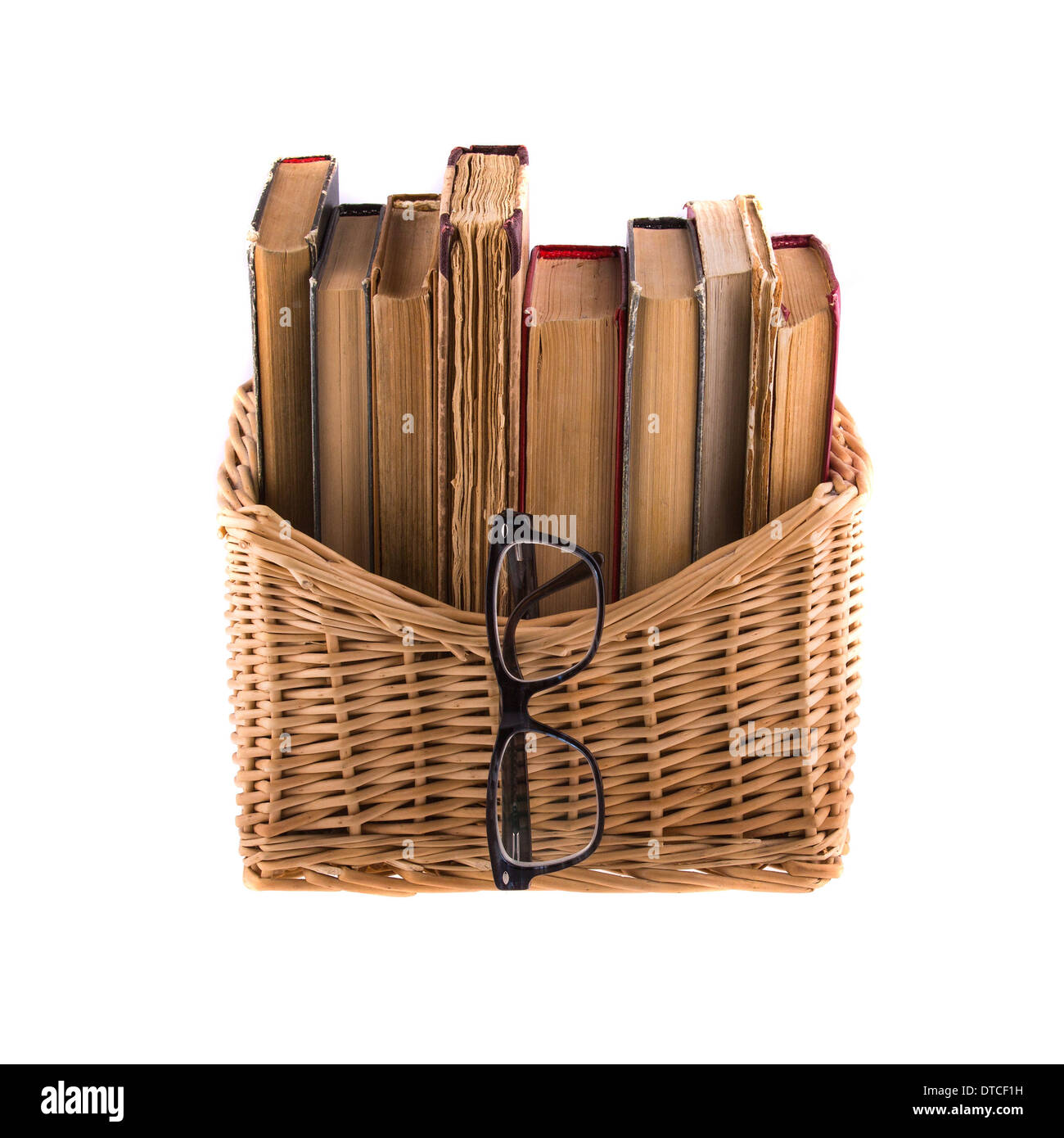 Stack of old antique books in a wicker basket and spectacles in thick ...
