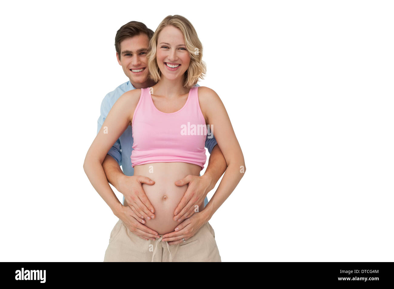 Expectant smiling parents holding mothers baby bump on white background ...