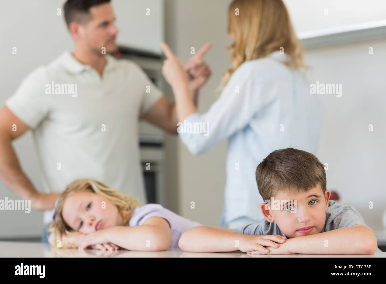 Children leaning on table while parents arguing Stock Photo - Alamy
