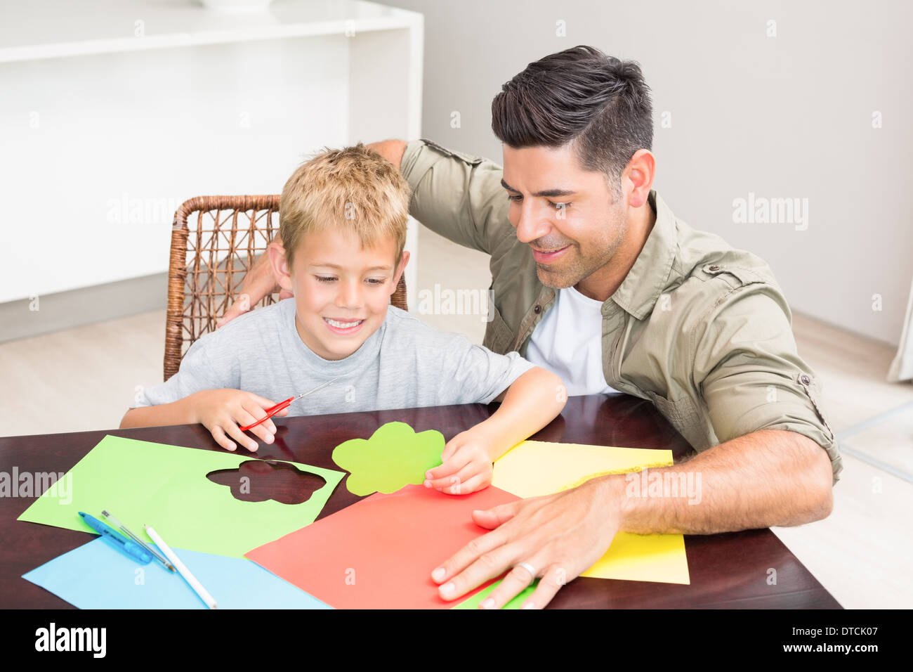 Father and son making paper shapes together at the table Stock Photo ...