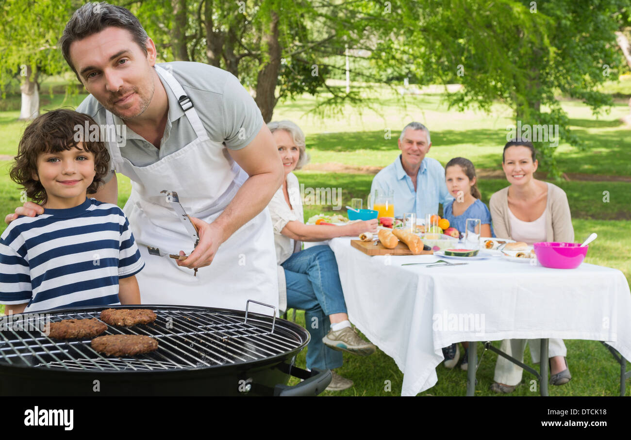 Father and son at barbecue grill with family having lunch in park Stock ...