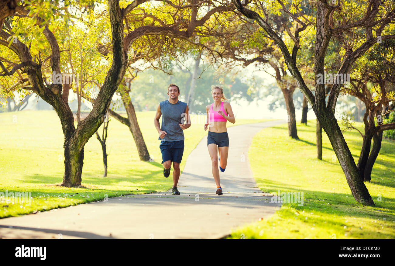Athletic couple running together. Sport runners jogging on park trail ...