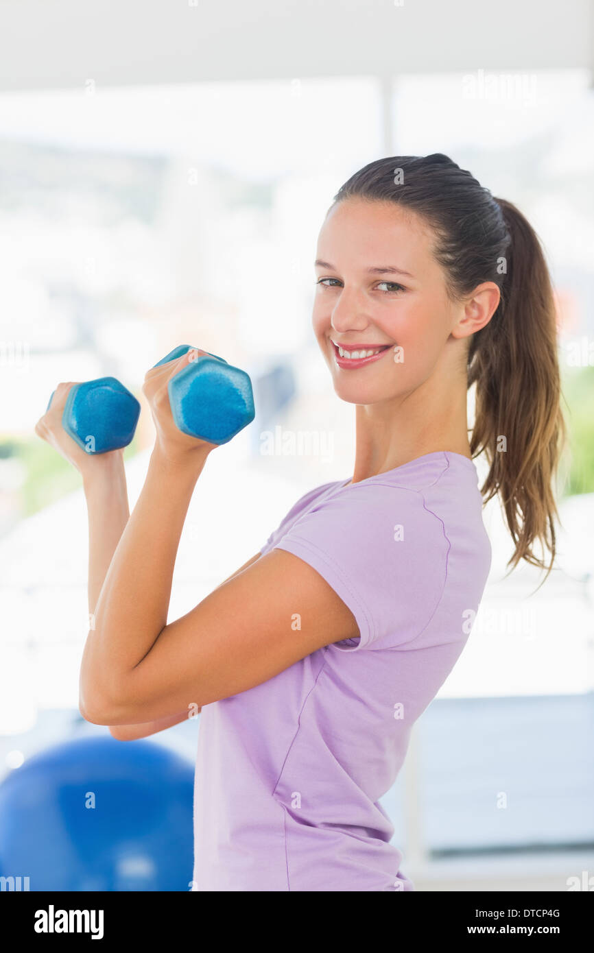 Side view of a smiling woman lifting dumbbell weights Stock Photo - Alamy