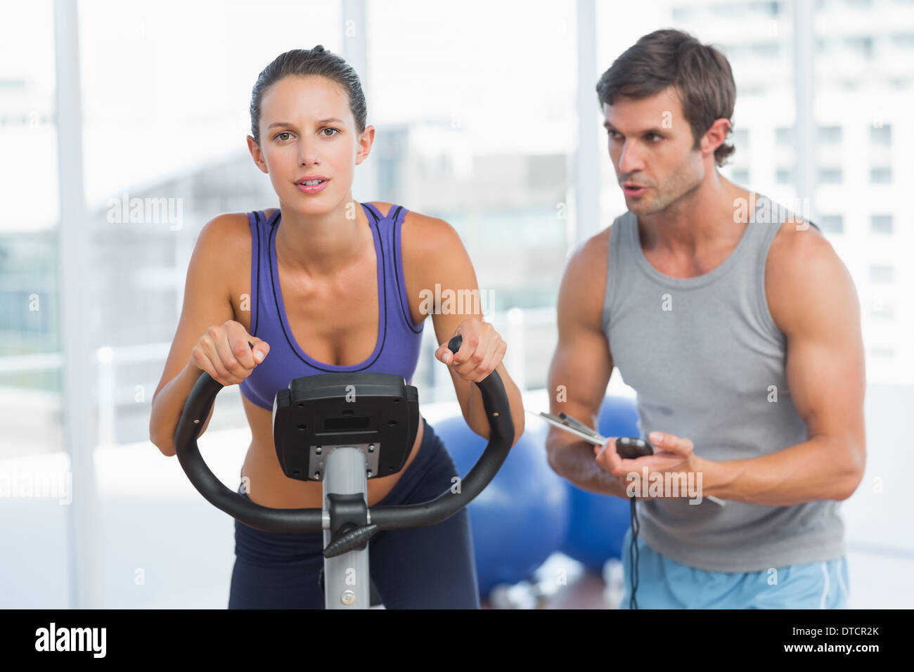 Trainer watching woman work out at spinning class Stock Photo - Alamy