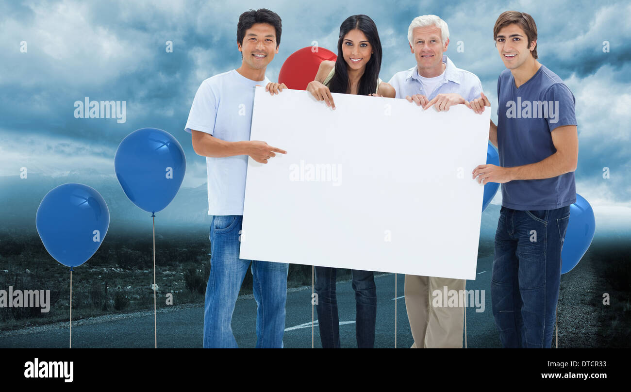 Composite image of smiling people holding and showing a big sign Stock ...