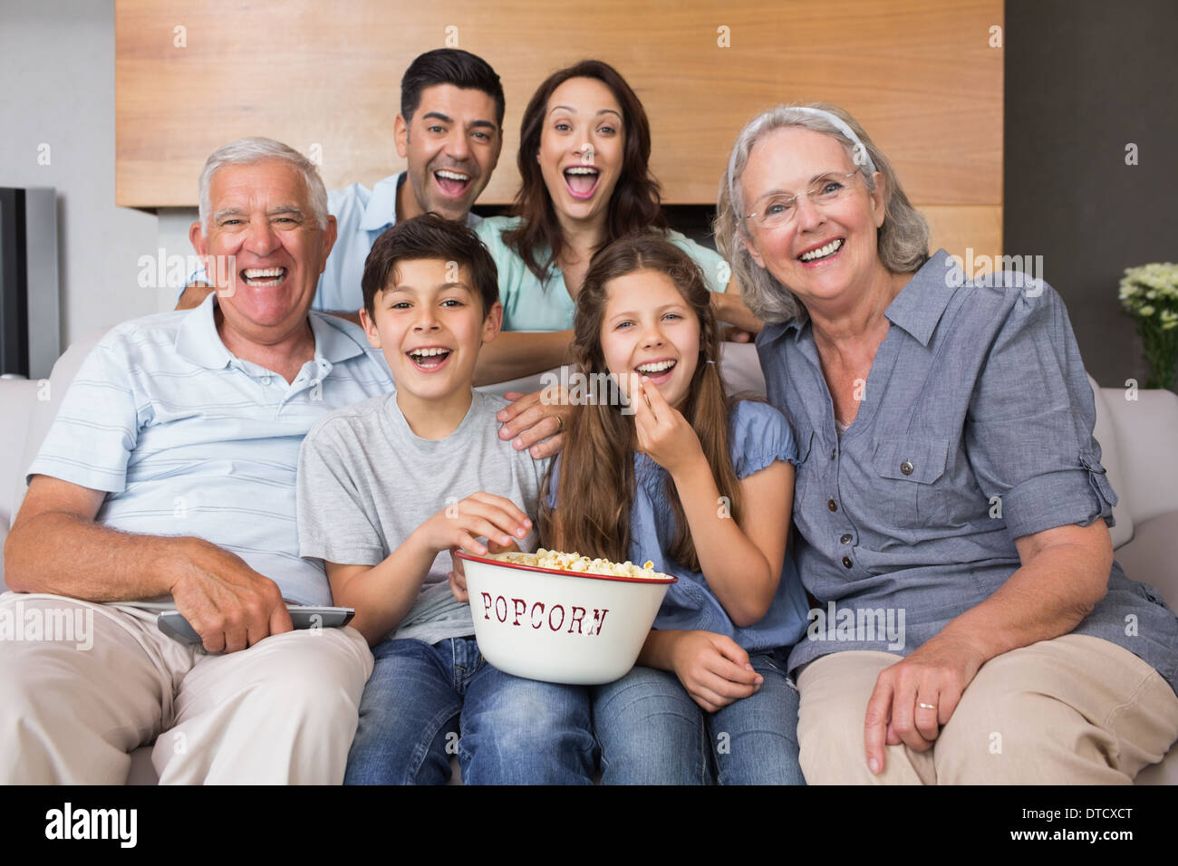 Portrait of happy extended family watching tv on sofa in the living ...