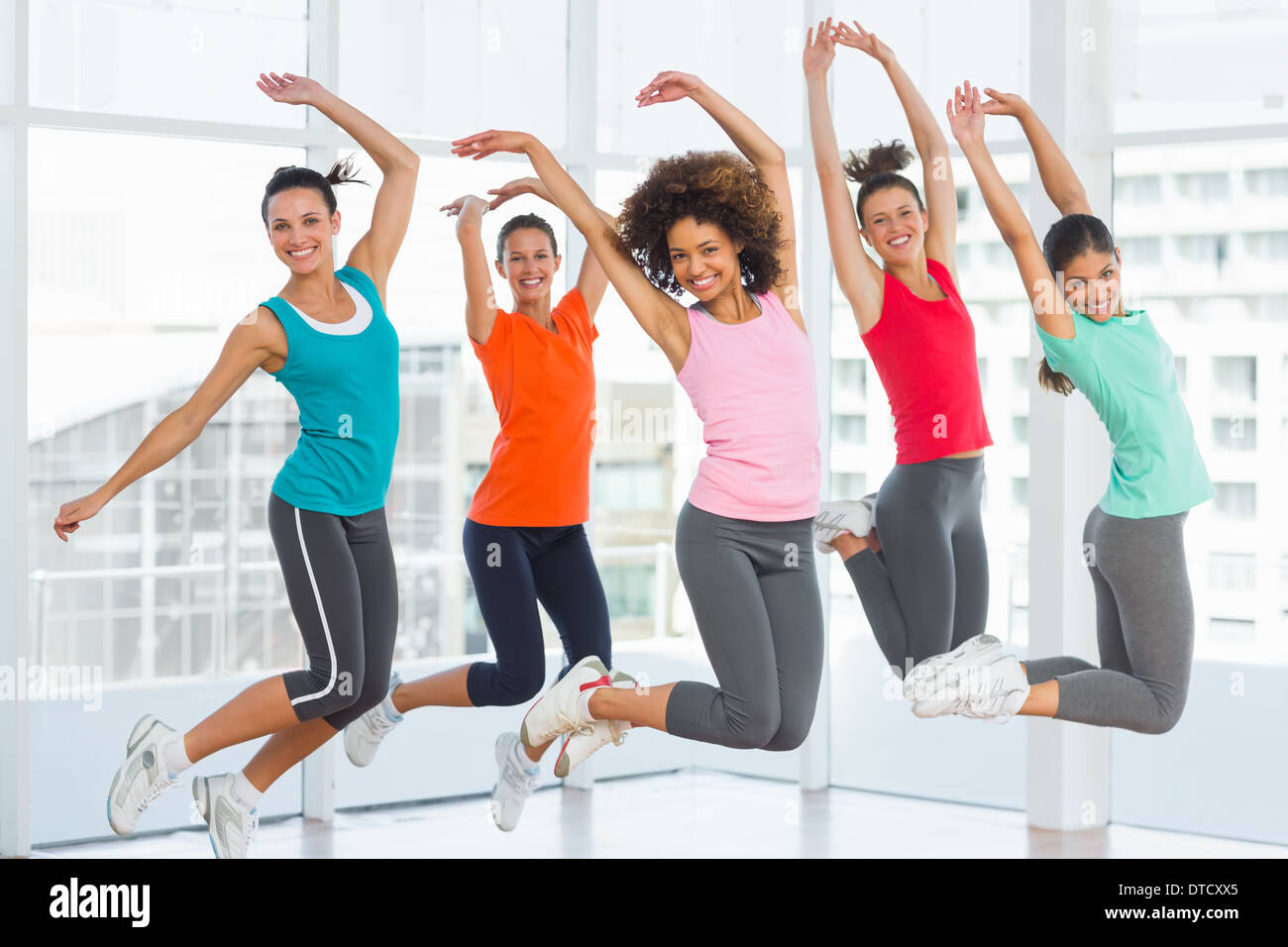 Fitness class and instructor jumping in fitness studio Stock Photo - Alamy