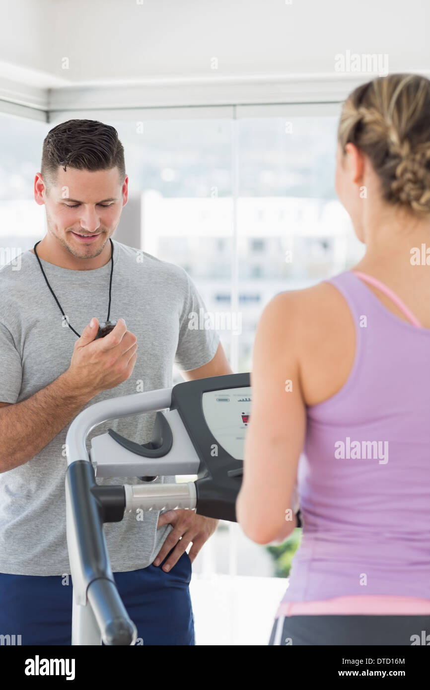 Trainer watching woman exercising at gym Stock Photo - Alamy