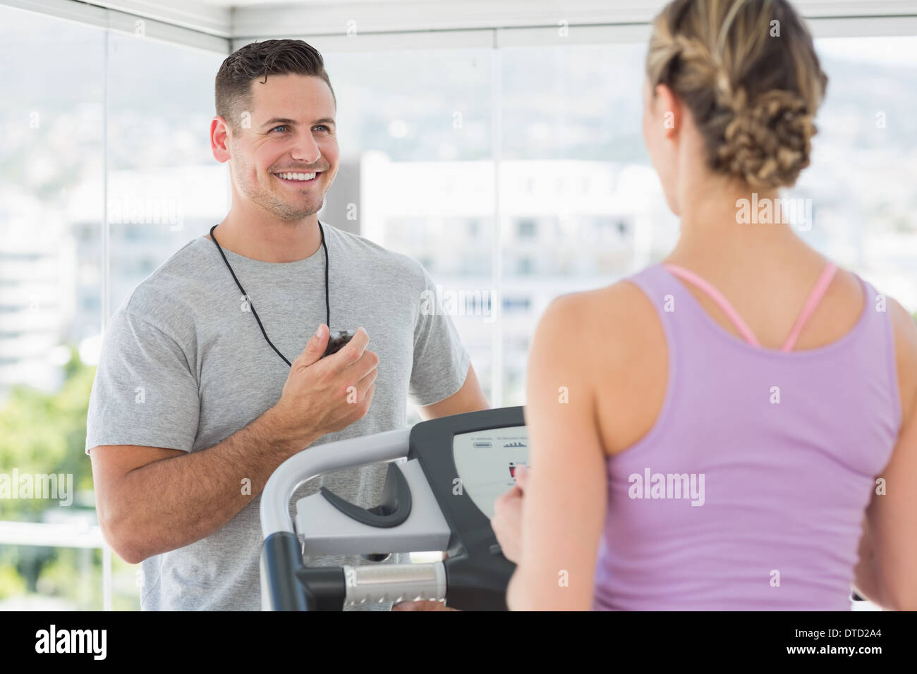 Trainer helping woman on treadmill Stock Photo - Alamy