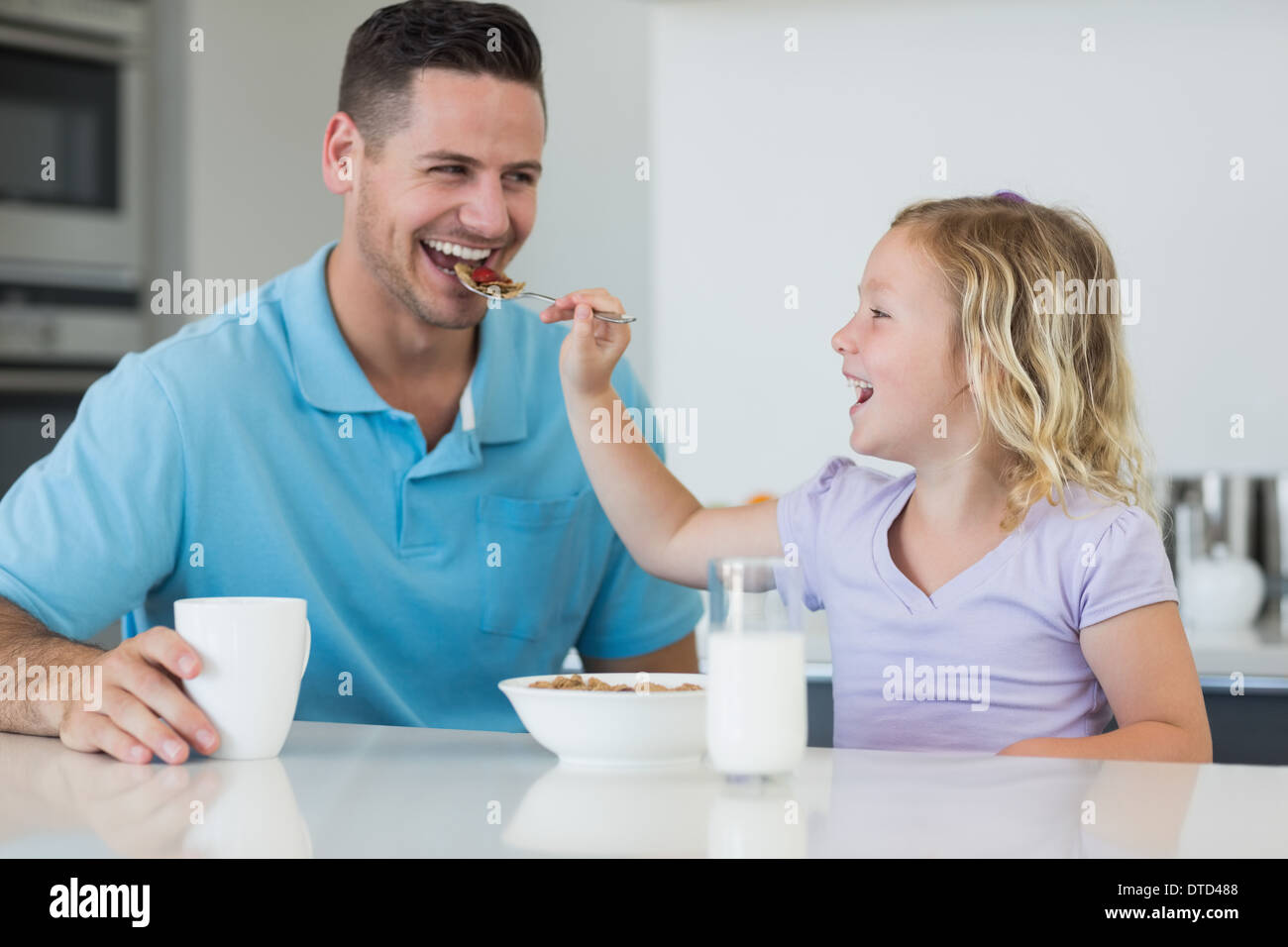 Daughter feeding cereals to father at table Stock Photo - Alamy
