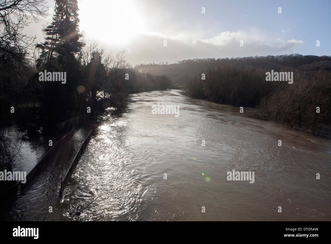 Lens flare image of sun setting over flooded river, a flood footbridge ...