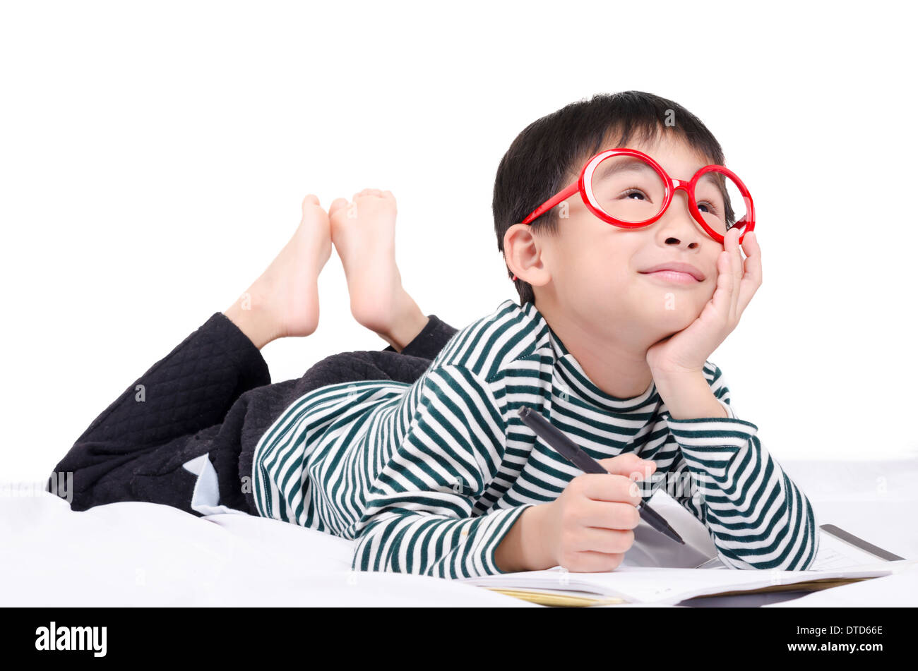 Smart child lying on bed writing and thinking Stock Photo - Alamy