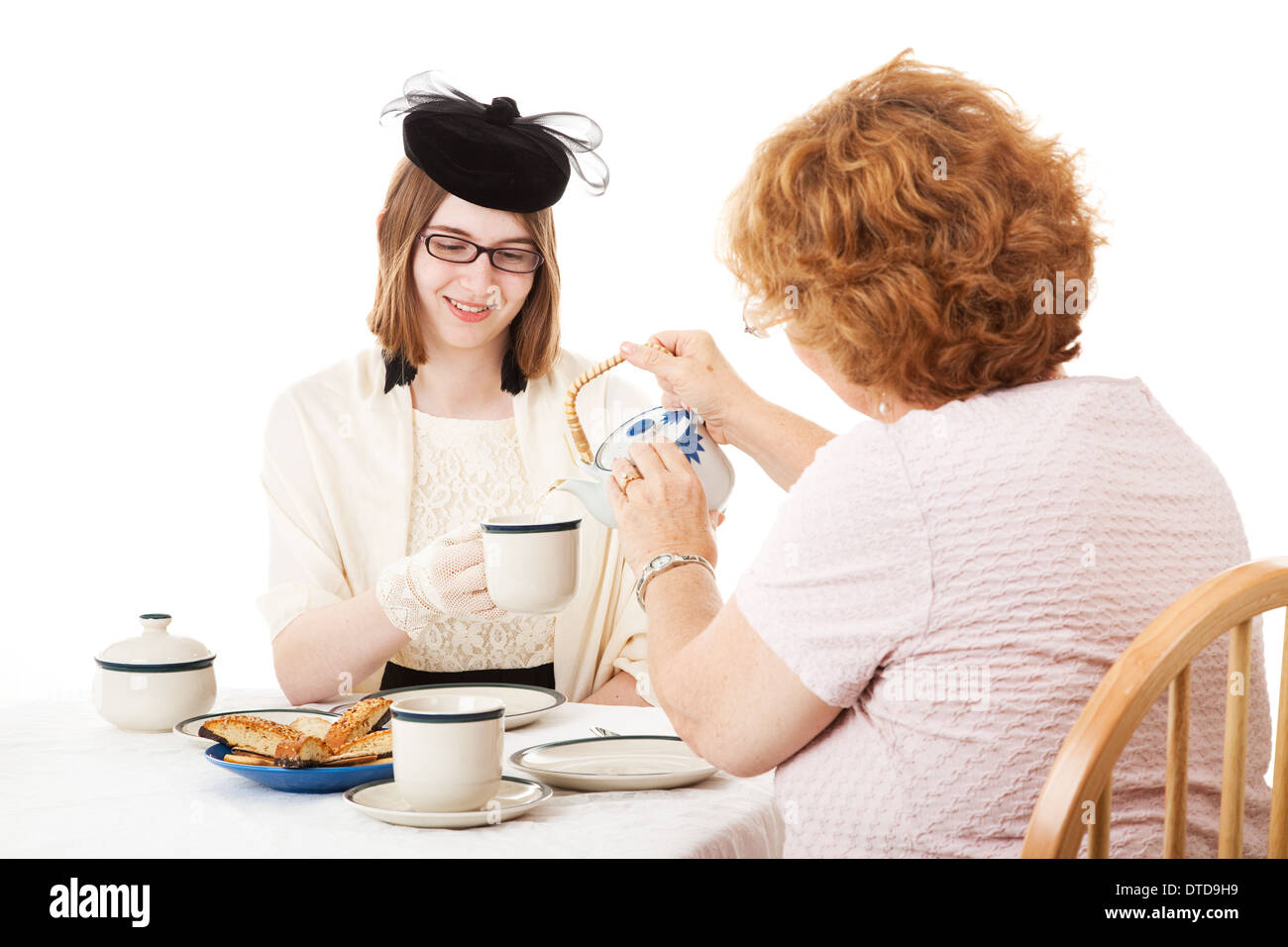 Mother pouring tea for her teen daughter at their tea party. Isolated ...