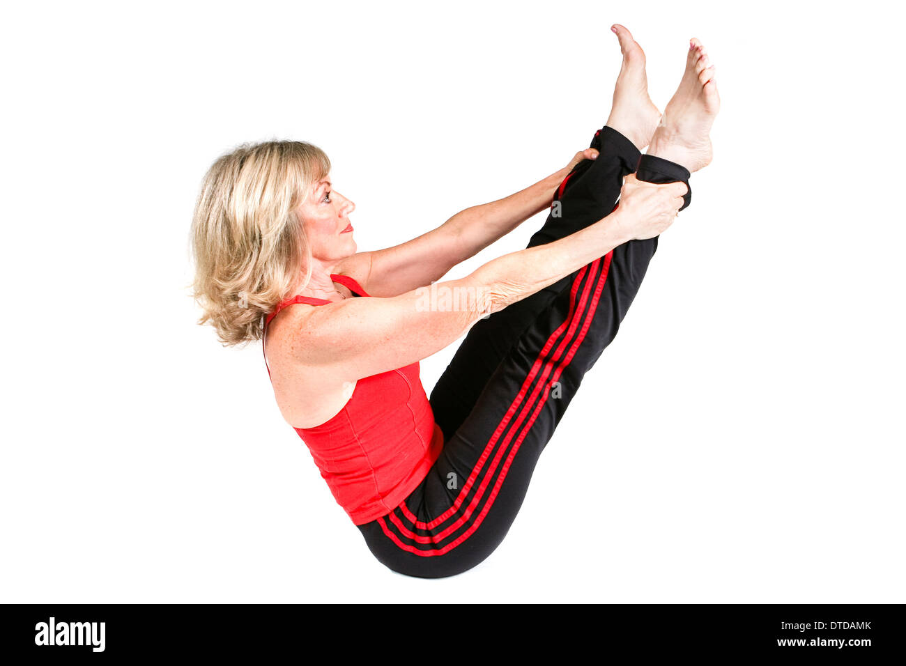 Very fit woman in her early sixties doing pilates. Isolated on white ...