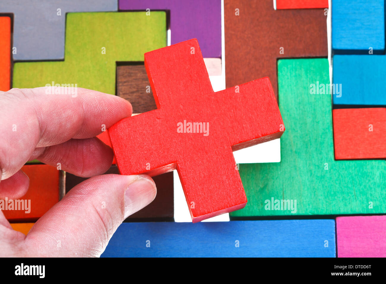 putting cross shaped block in wooden multicoloured puzzle isolated on ...