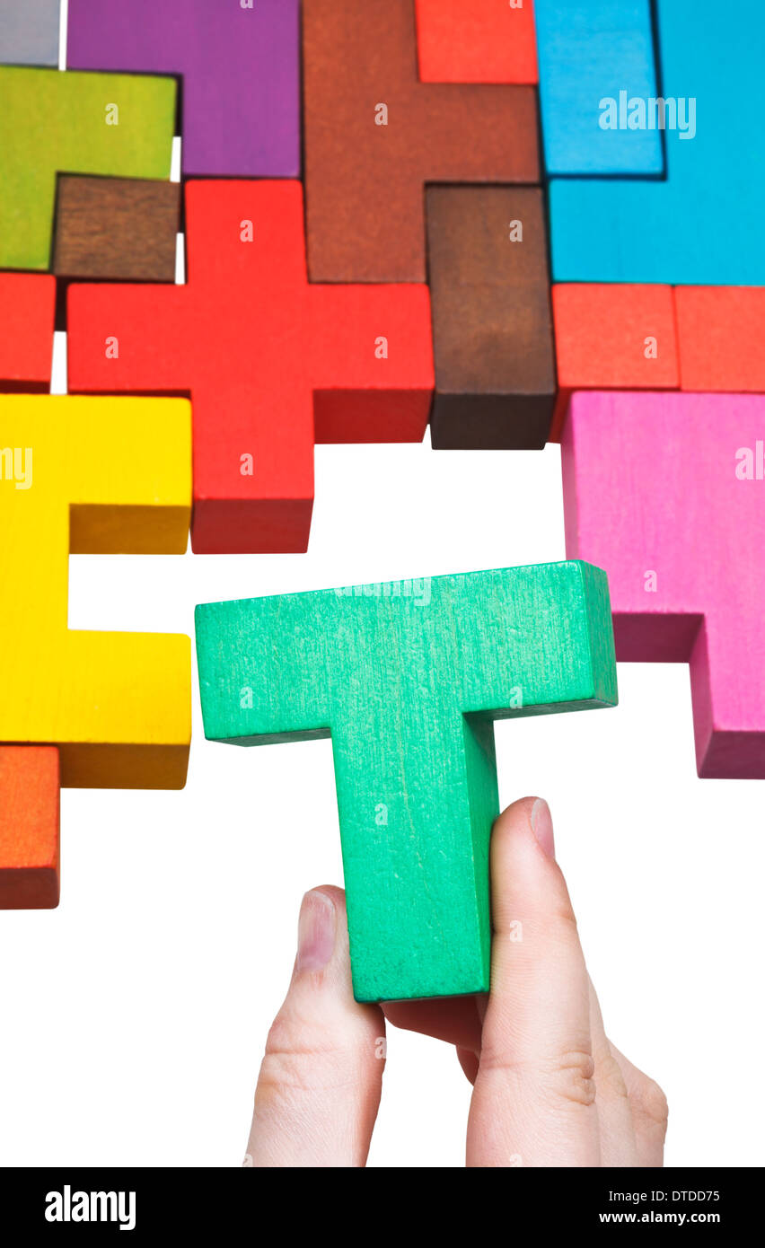 putting T-shaped block in wooden multicoloured puzzle isolated on white ...