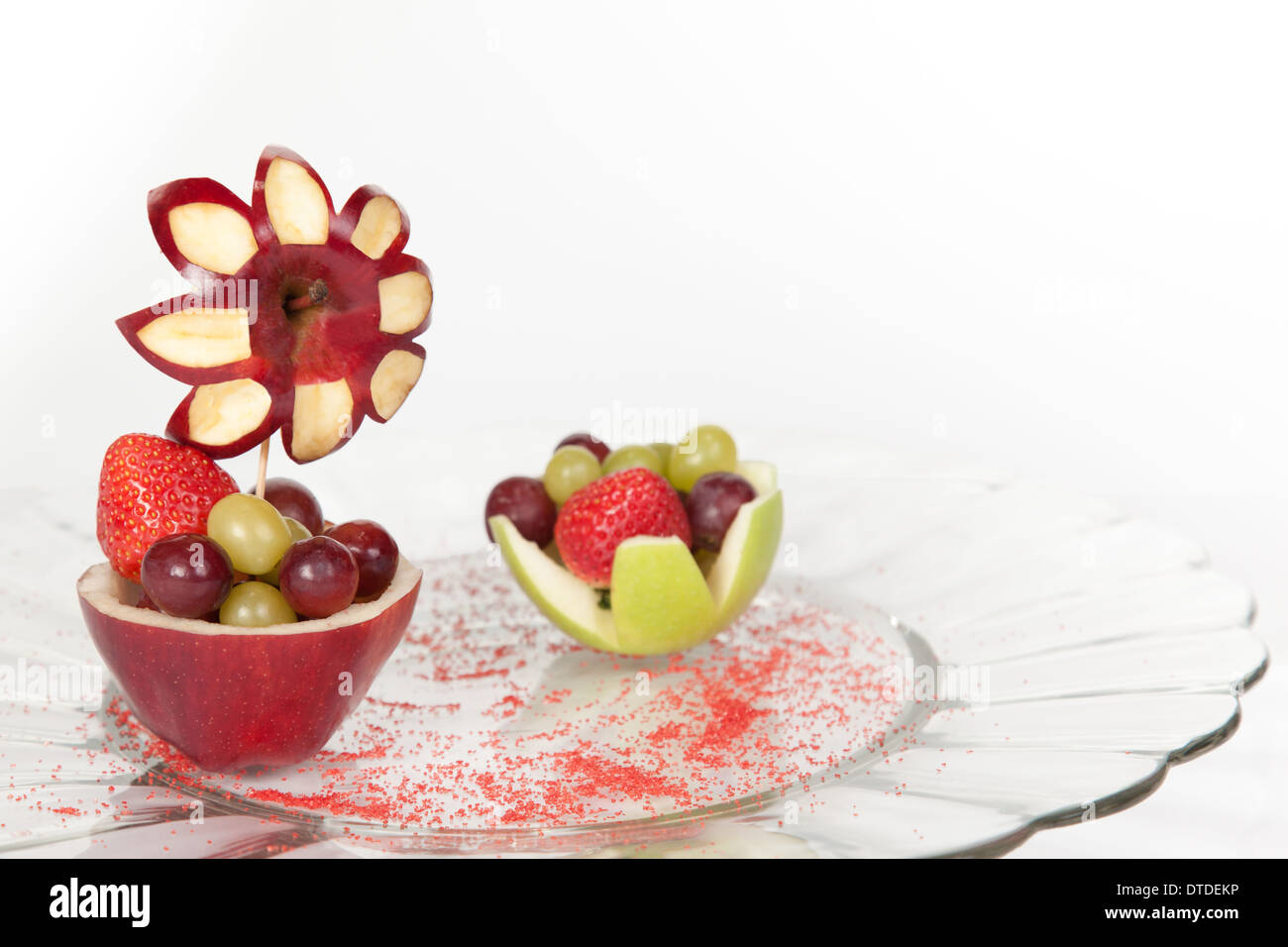 Apple carved into a flower with fruit in the base on a white background ...
