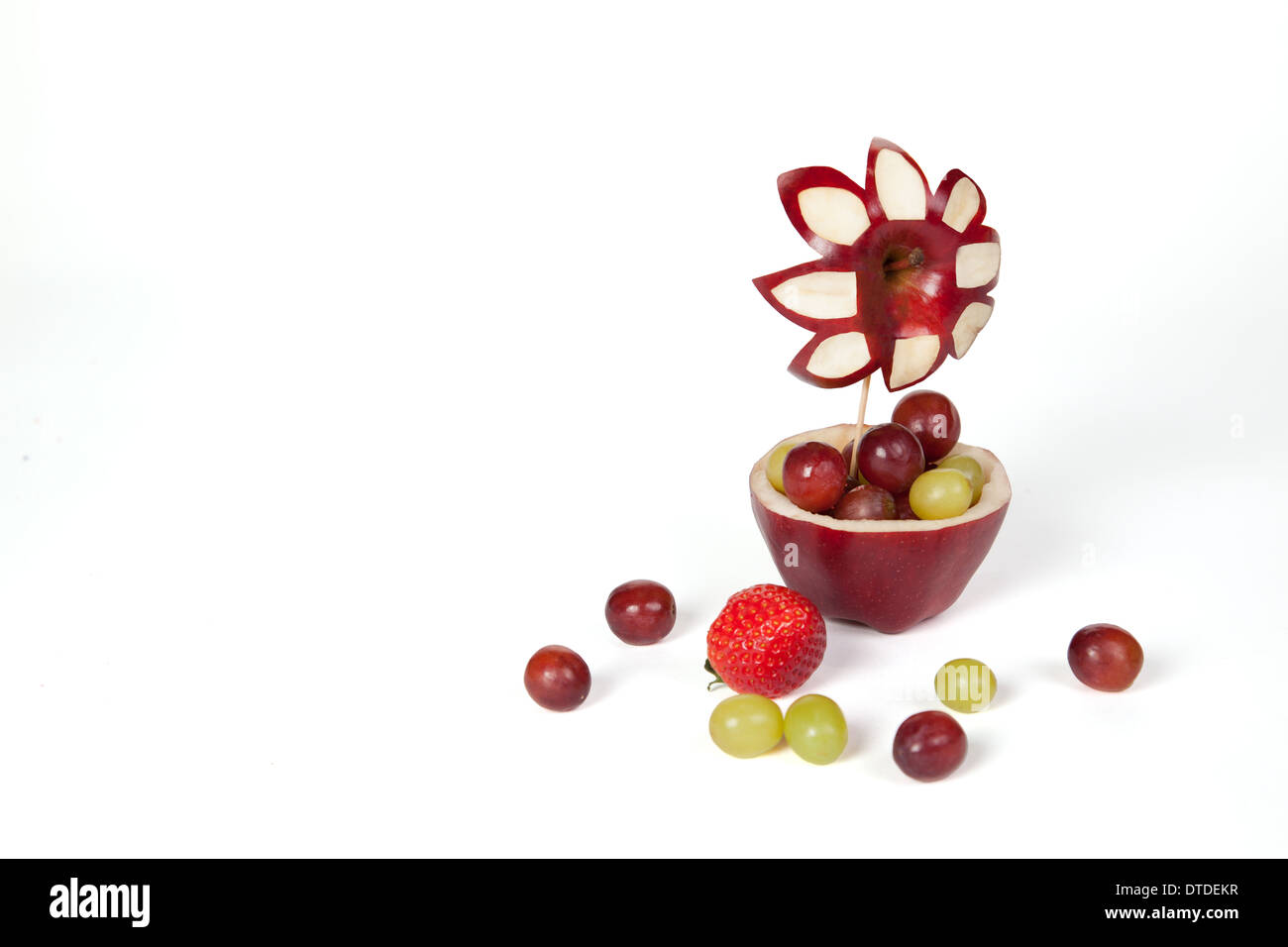 Apple carved into a flower with fruit in the base on a white background ...