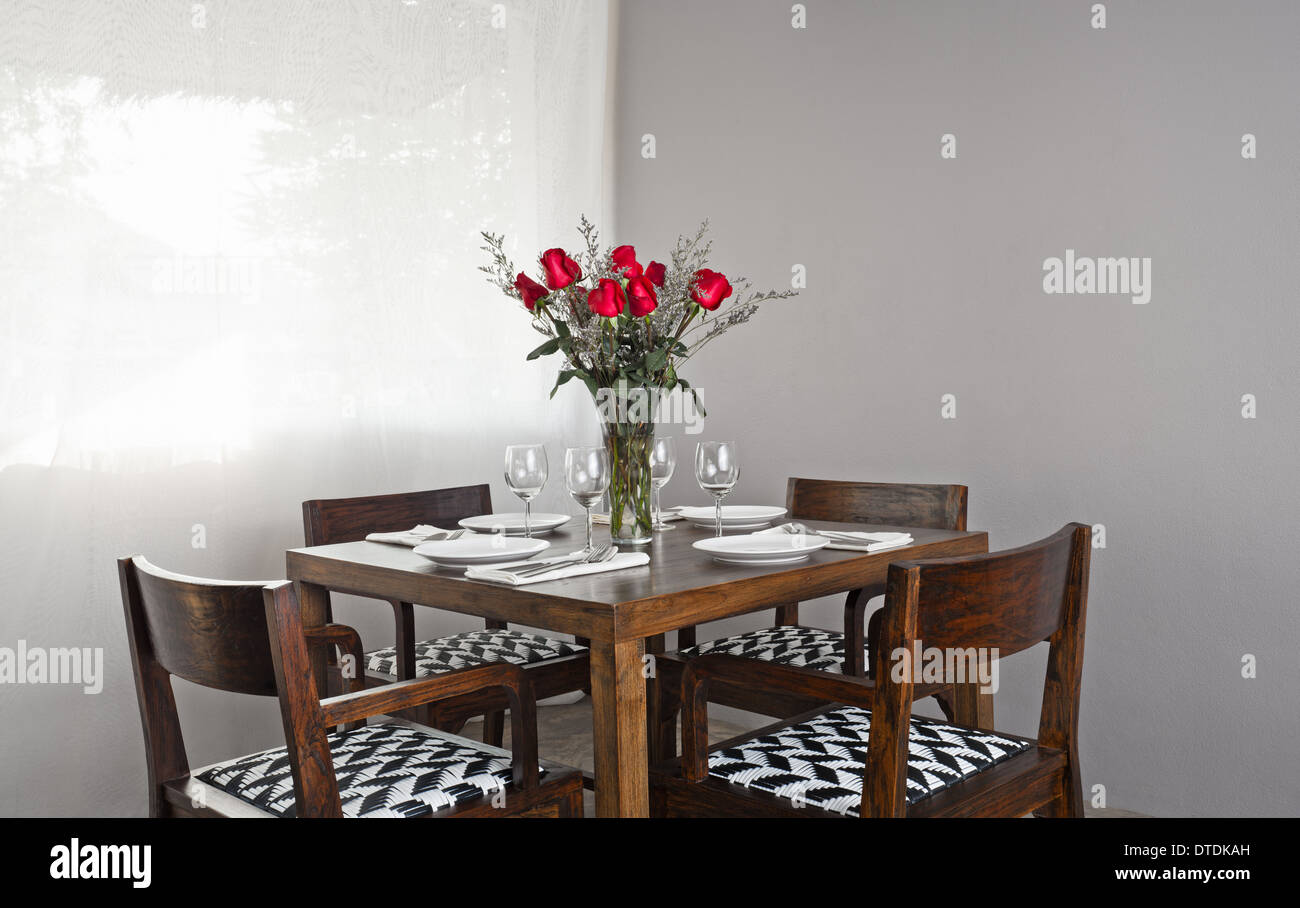 Dinner table setup for four with red roses Stock Photo - Alamy