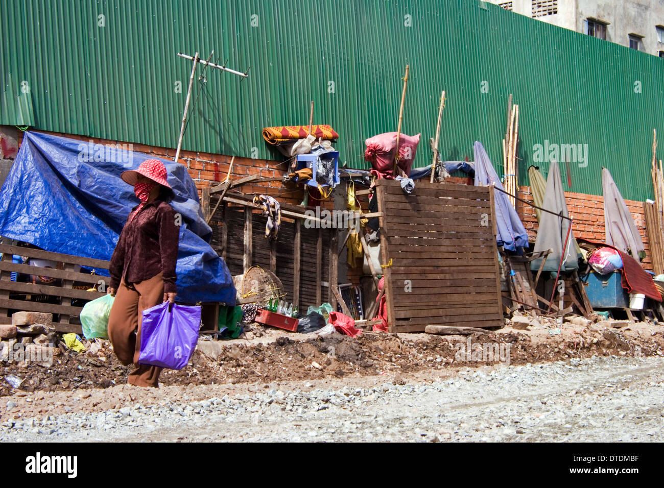 A woman is walking past a squatters home and posessions that are ...