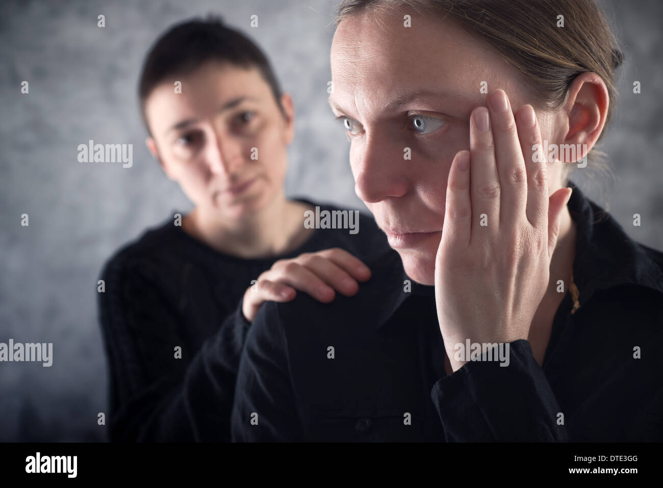 Comforting friend. Woman consoling her sad friend with hand on shoulder ...