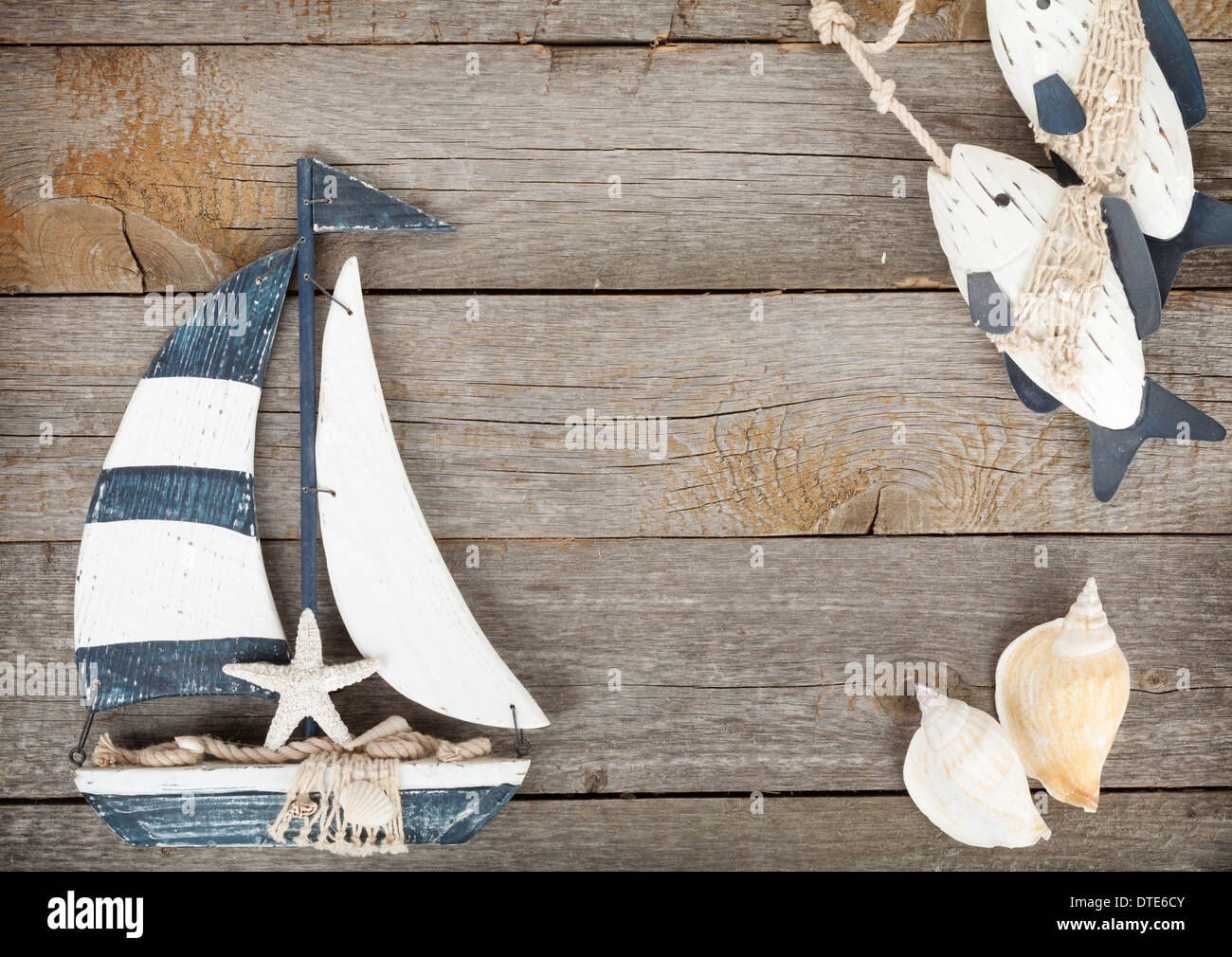 Toy sailboat and fish with seashells on a wooden background with copy ...