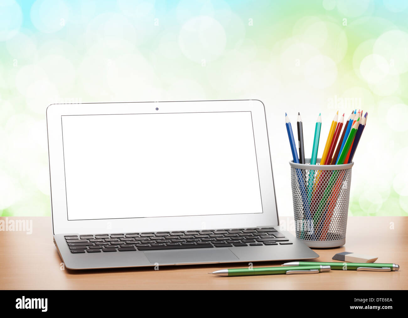 Laptop with blank screen and colorful pencils on table over sunny day ...