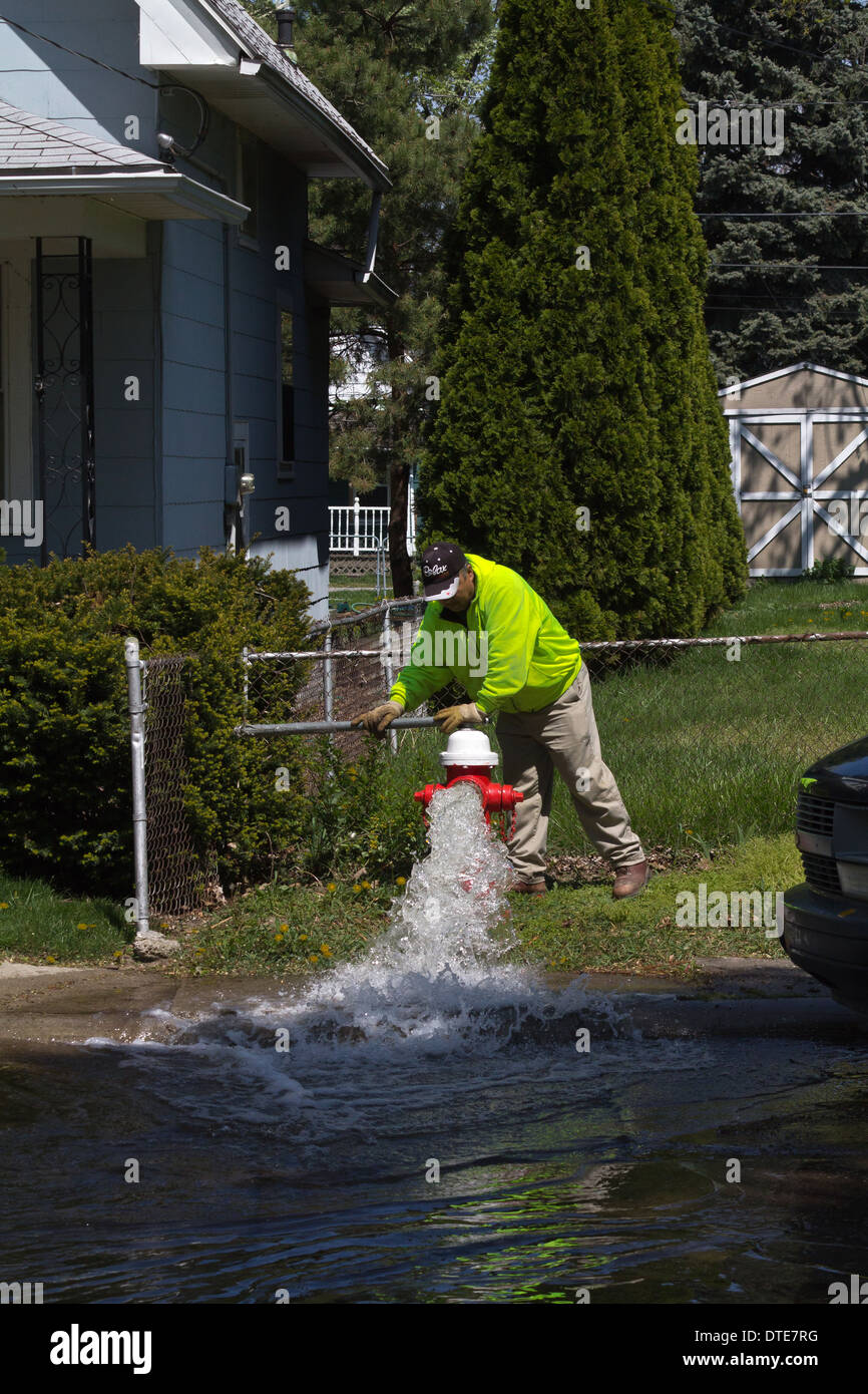 A damaged red fire hydrant spraying water on the city street with ...