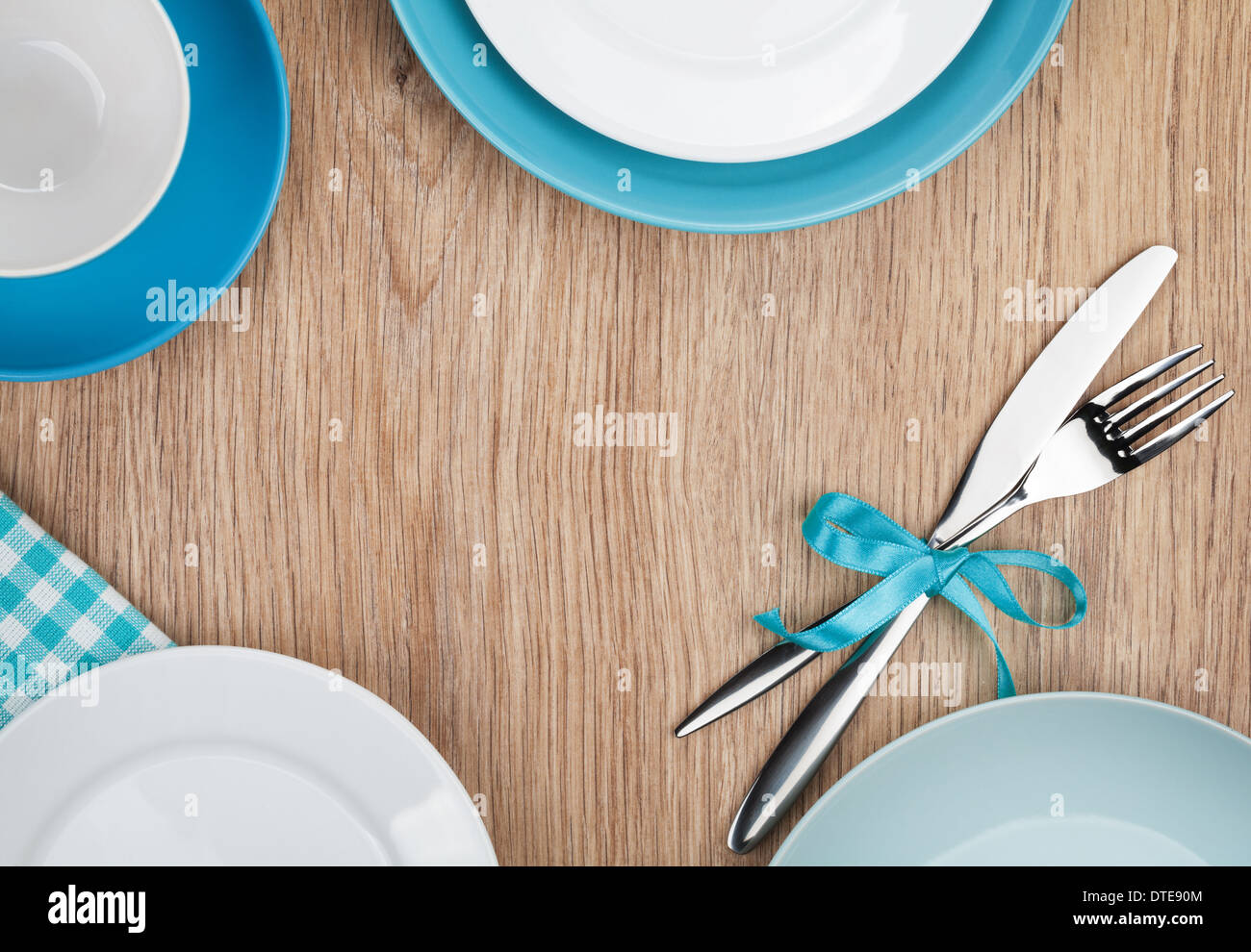 Kitchen utensils, plates, silverware over wooden table with copyspace ...