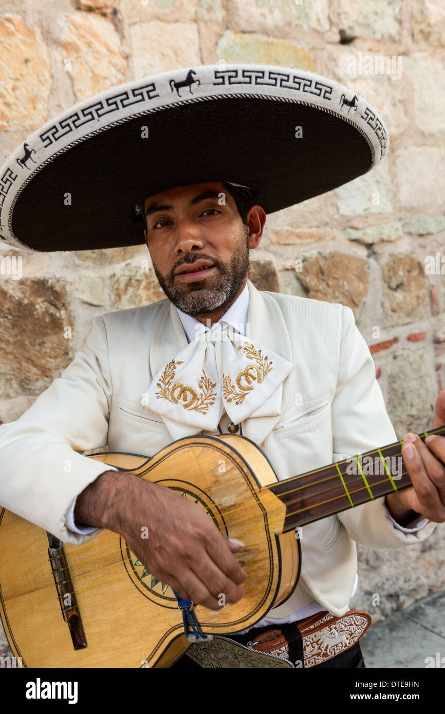 A mariachi musician dressed in traditional charro costume playing a ...