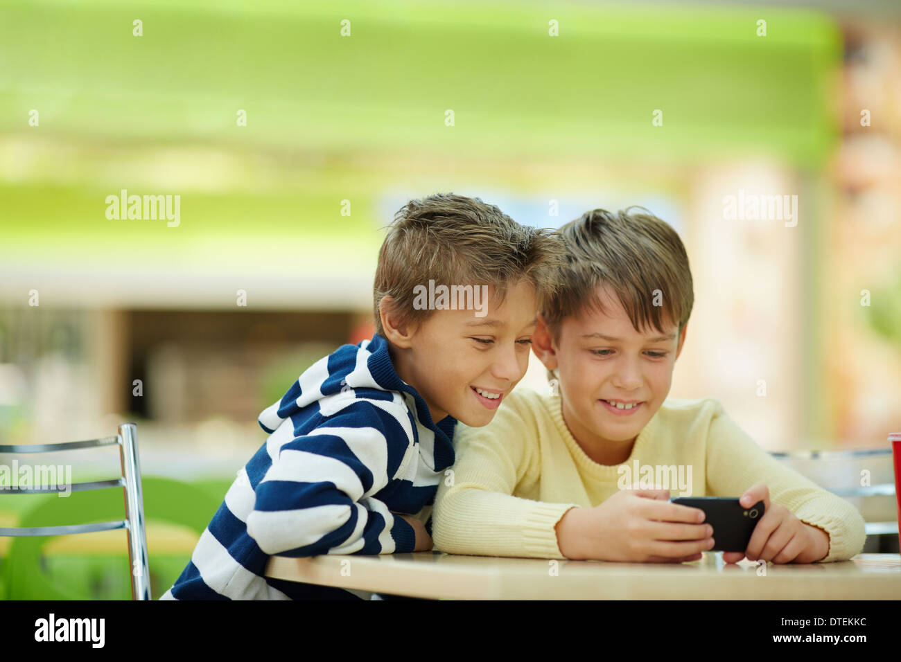 Two boys watching smartphone photos Stock Photo - Alamy