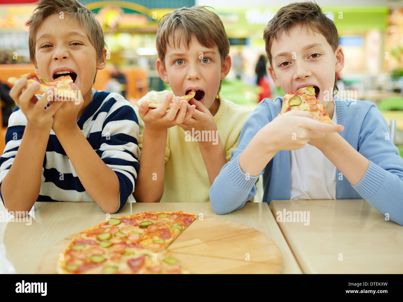 Three little boys eating pizza at cafe Stock Photo - Alamy