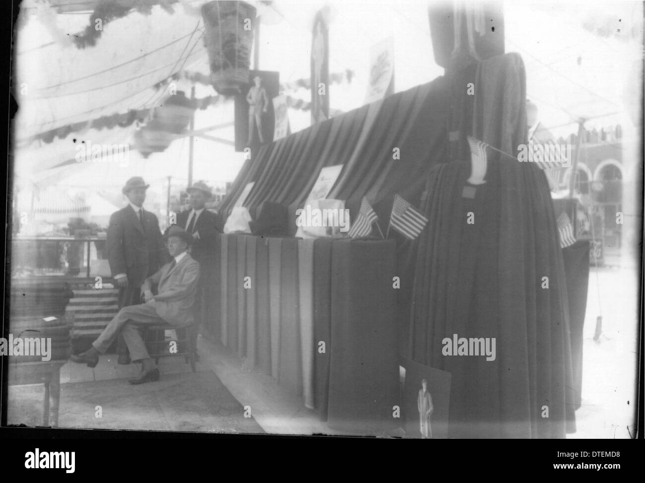 A photograph of three men seated at a booth during a state fair. The ...
