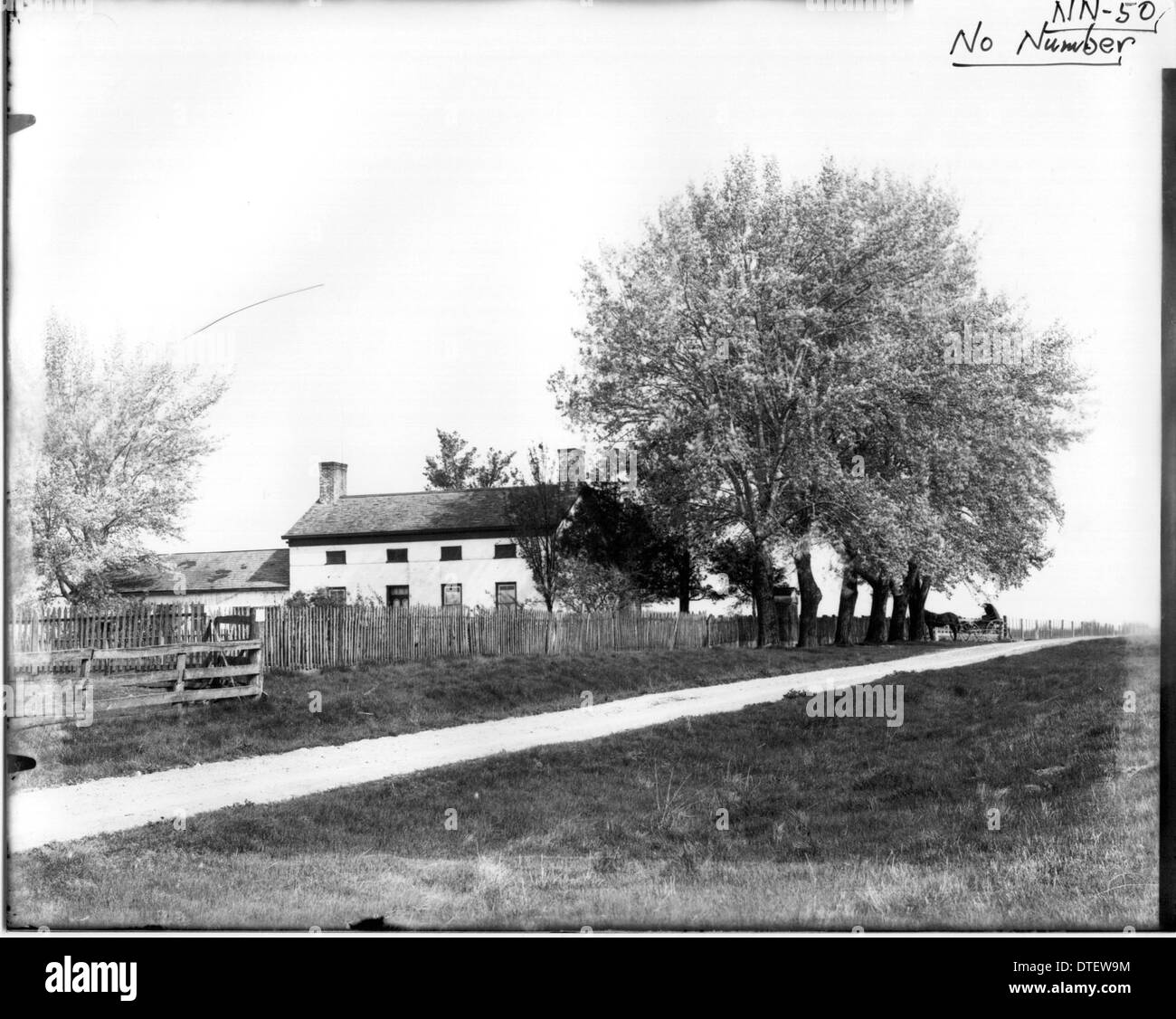 This photograph shows a rural house with a fence, capturing a simple ...