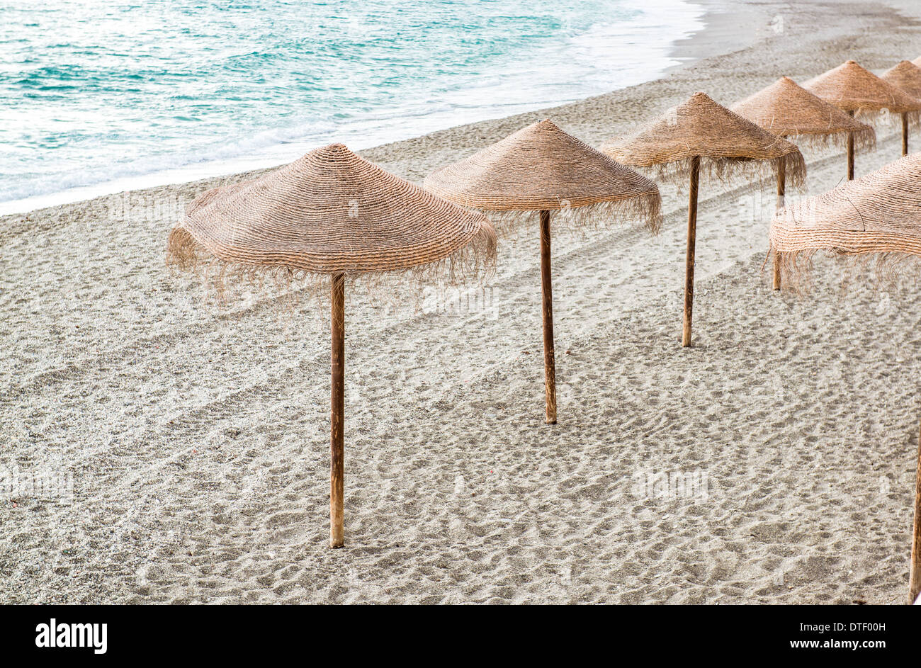 Straw parasols on empty beach Stock Photo - Alamy