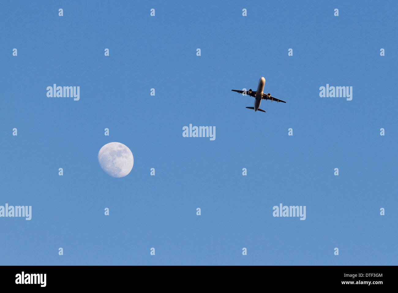 Plane flying across the sky with the moon in the background, England ...