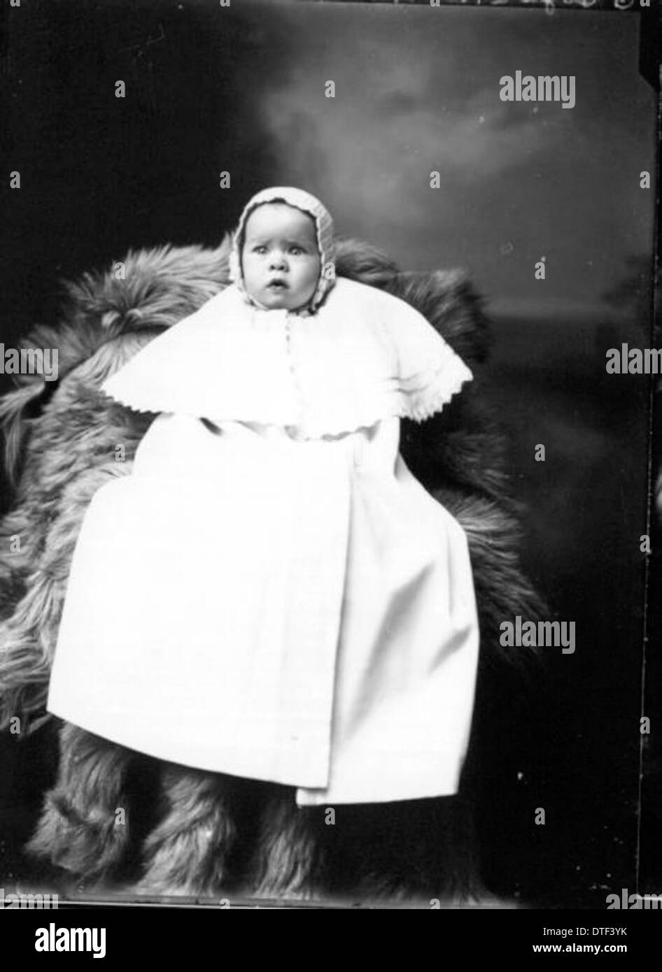 This 1912 portrait photograph shows a baby wearing a bonnet and sitting ...