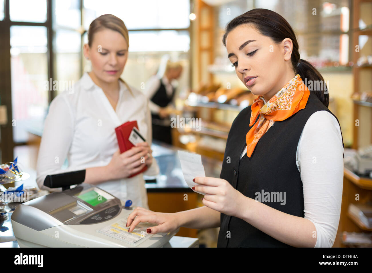 Client at shop paying at cash register with saleswoman Stock Photo - Alamy
