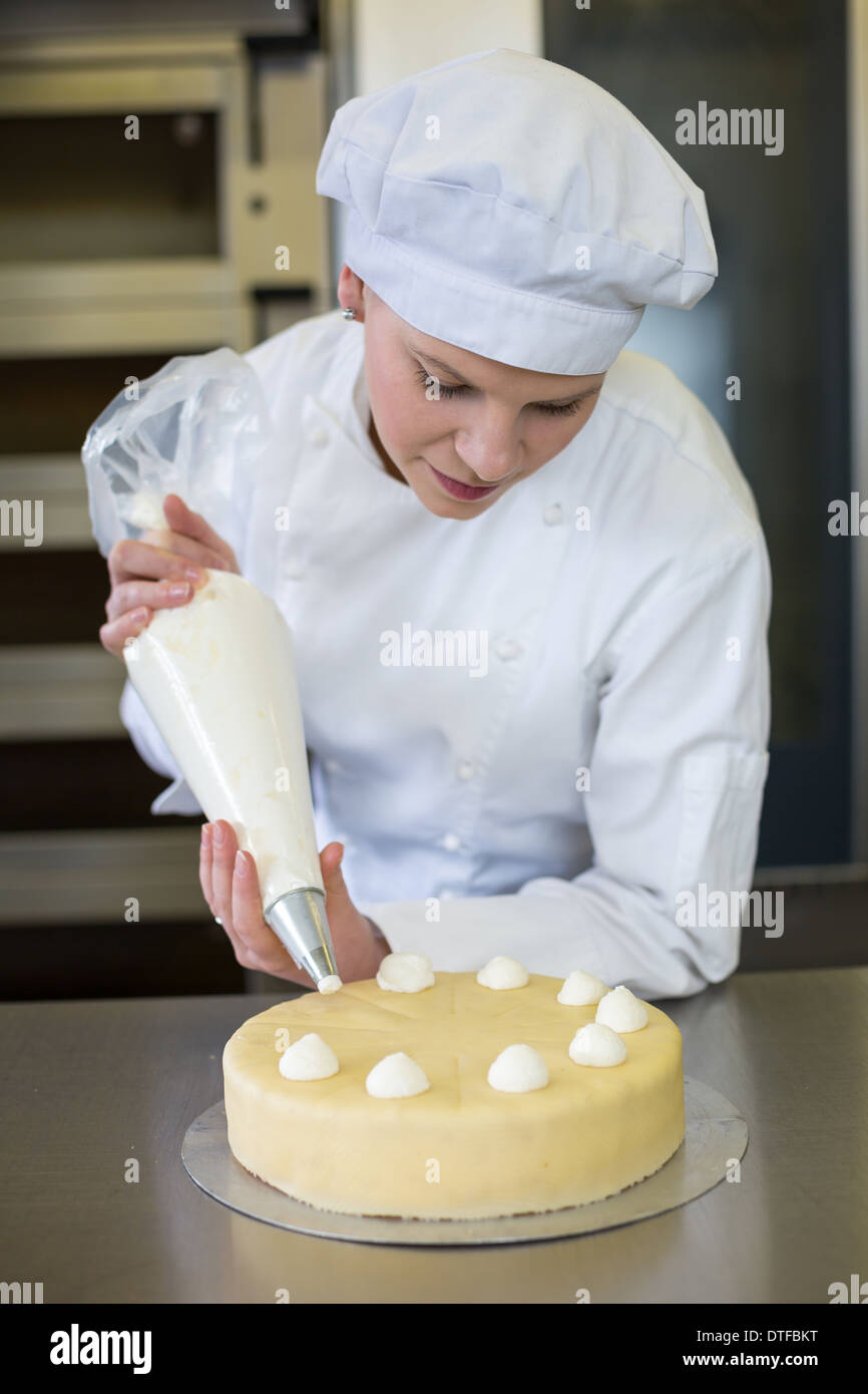 Female baker or confectioner prepares cake with whipped cream Stock ...