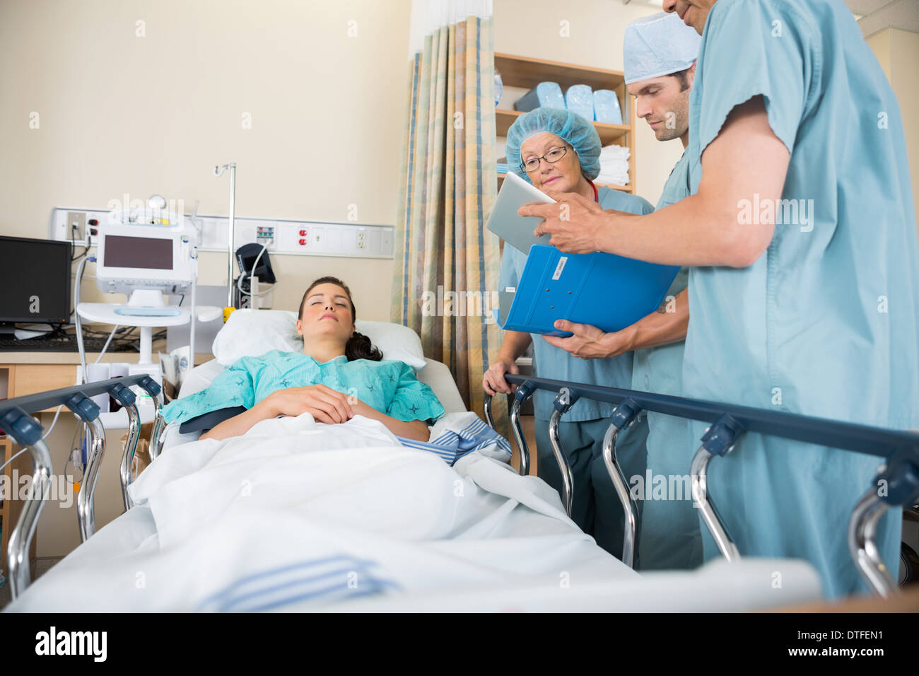 Nurses Discussing Patient's Report By Bed Stock Photo - Alamy