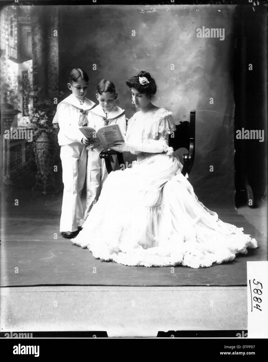 A 1904 photograph of Mrs. Harvey Cook reading with two boys, captured ...