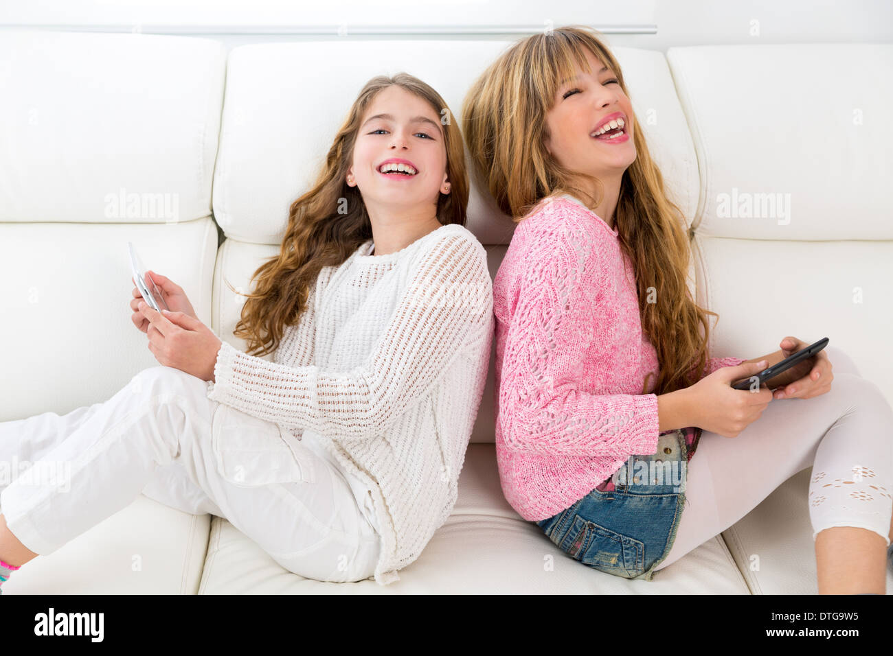 Children friends kid girls having fun playing back to back with tablet ...