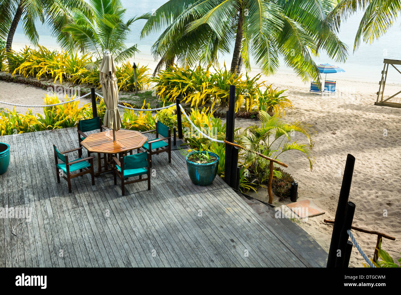 A beautiful weathered tropical resort patio sundeck along a beach lined ...